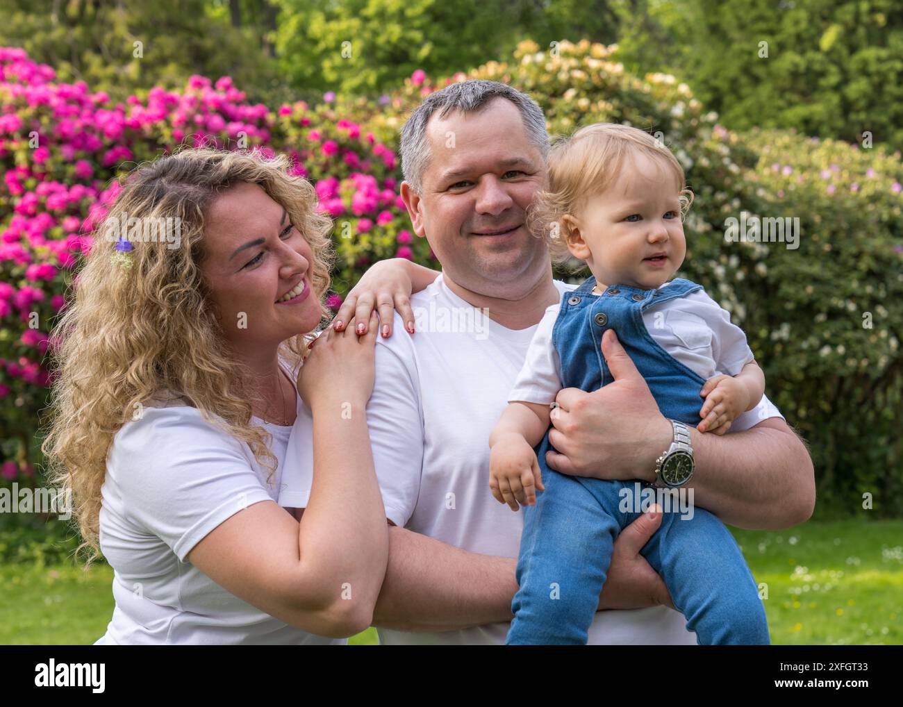 Porträt einer glücklichen Familie. Mutter mit welligen Haaren steht ...