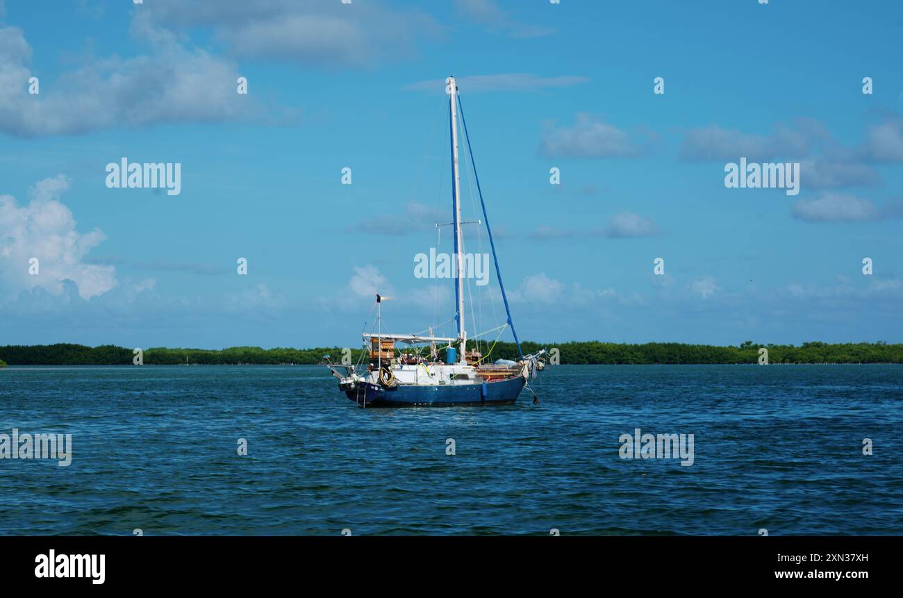 Ein einsames Segelboot, das auf ruhigem Wasser unter einem klaren ...