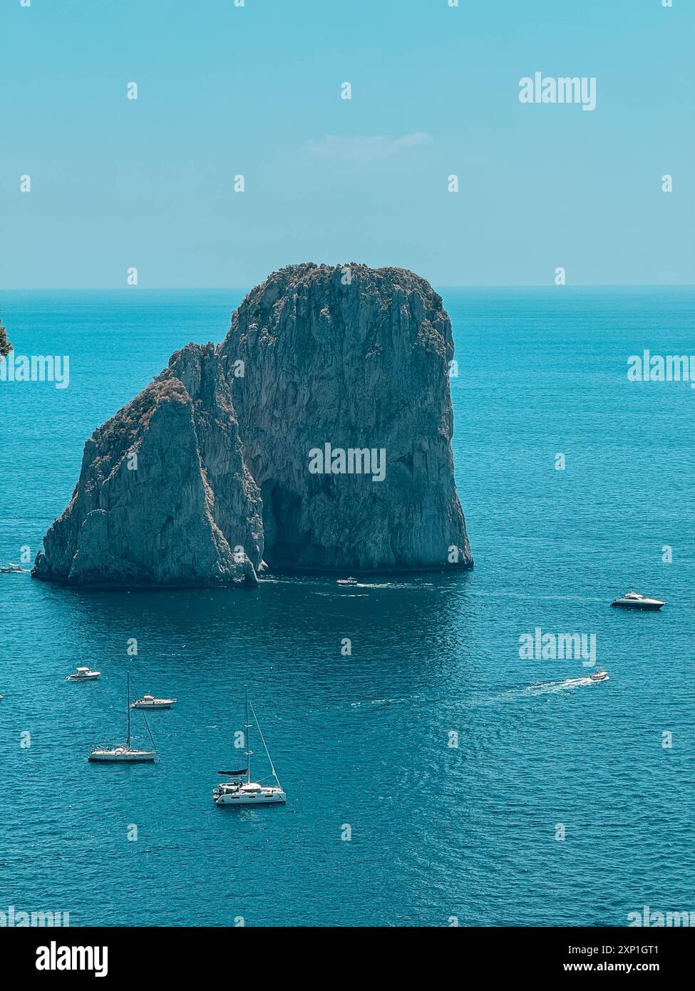Ein großer Felsen liegt mitten im Meer, mit mehreren Booten im Wasser ...