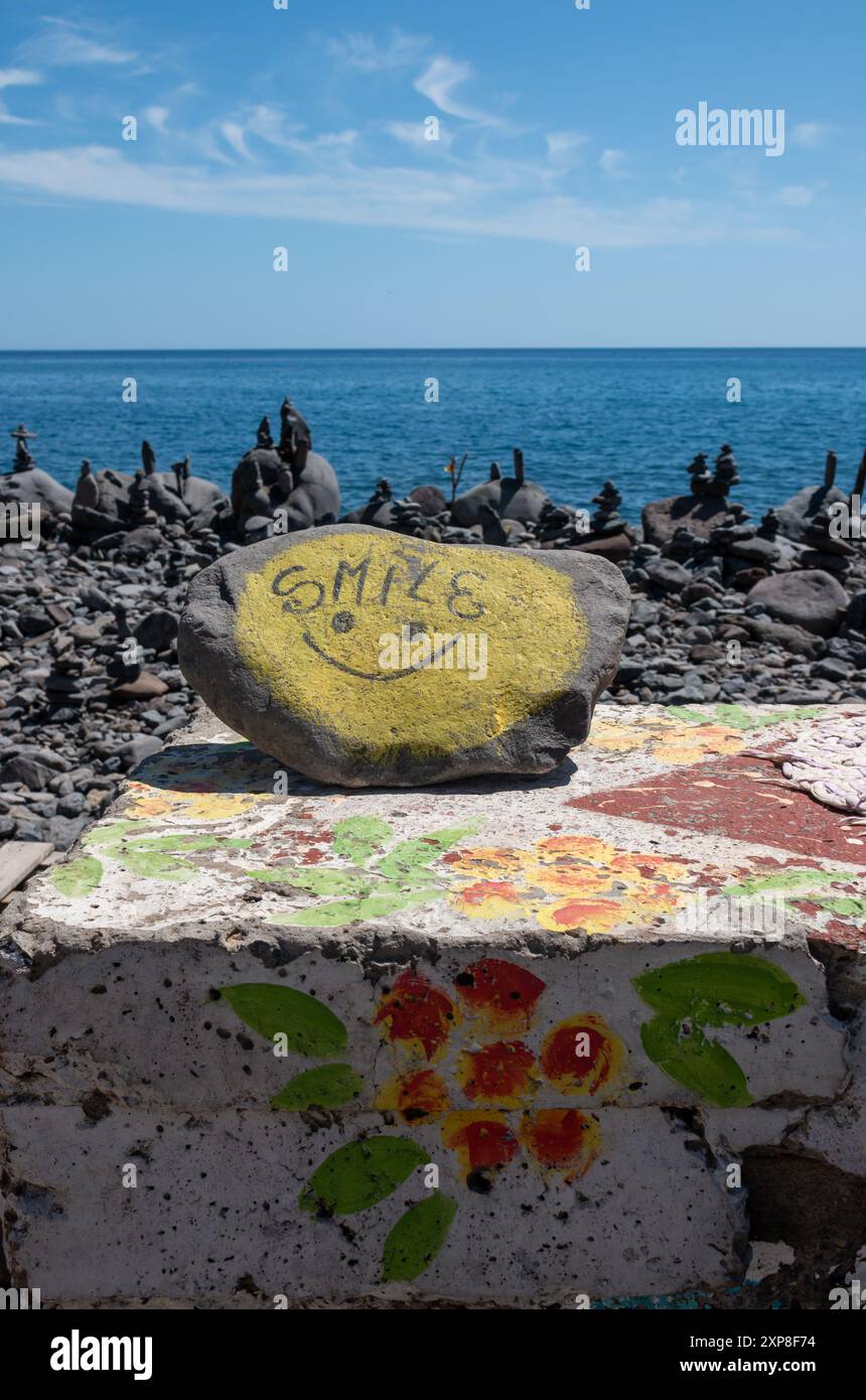 Großer gelb bemalter Kieselstein auf einem bemalten Zaun eines Strandes ...