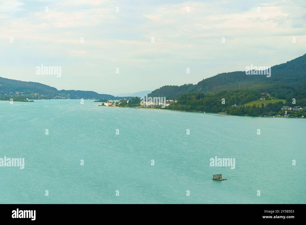 Ein ruhiger See reflektiert die sanften Töne des Himmels, umgeben von ...