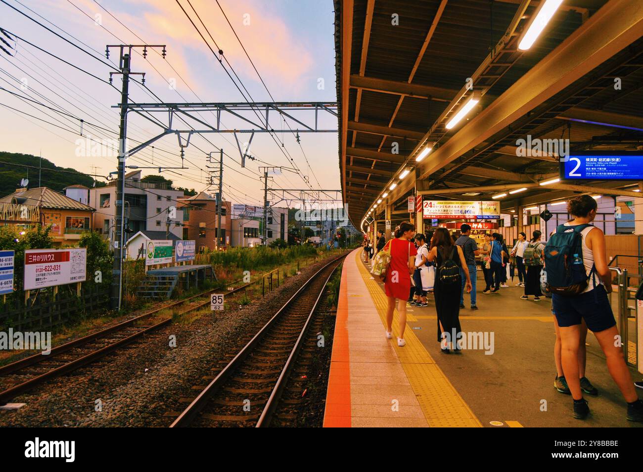 Eine lebhafte Szene an einem Bahnhof zwischen Yokohama und Tokio. Mit Pendlern, die auf dem ...