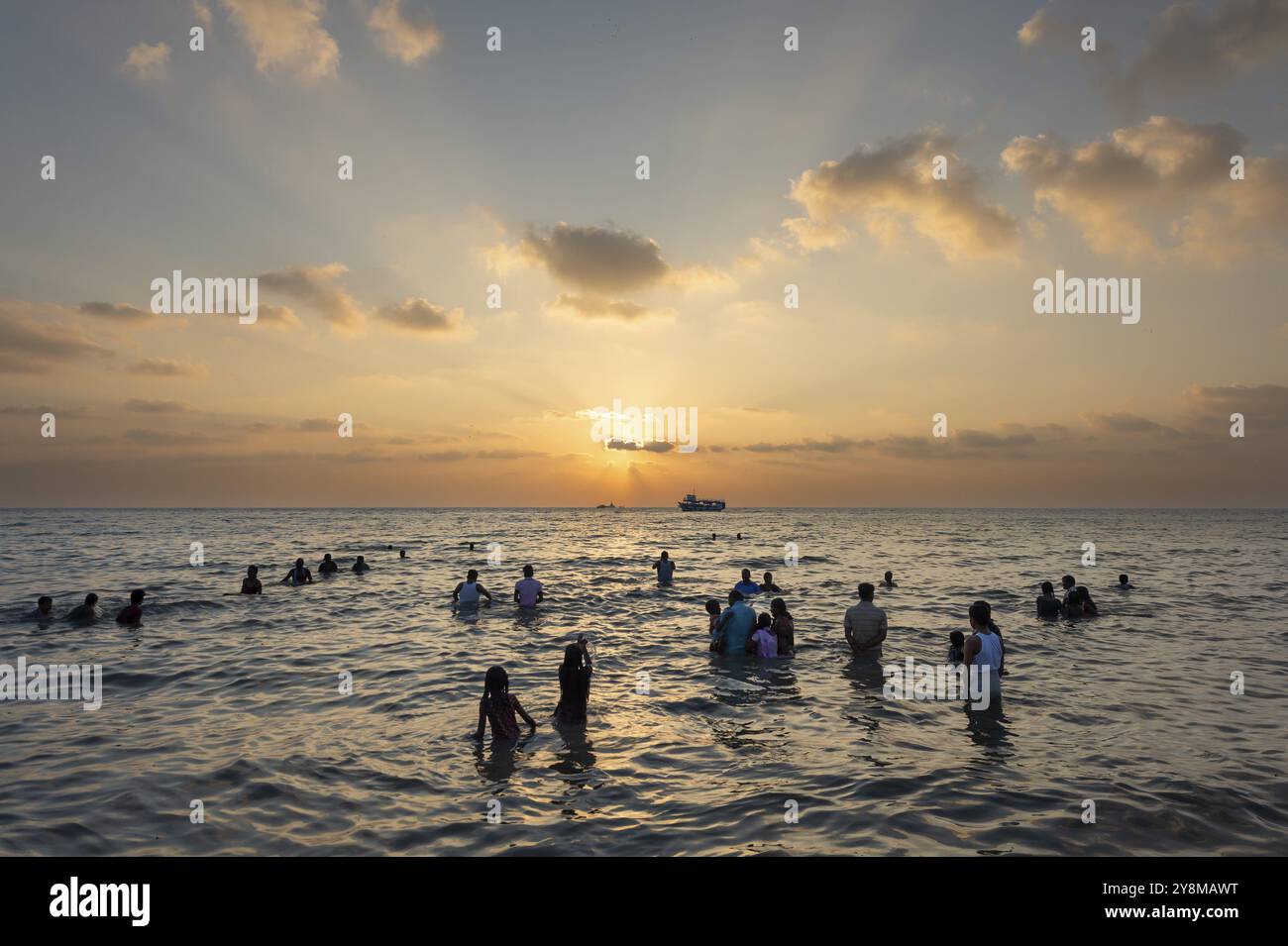 Hinduistische Pilger nehmen bei Sonnenaufgang ein heiliges Bad im Meer ...