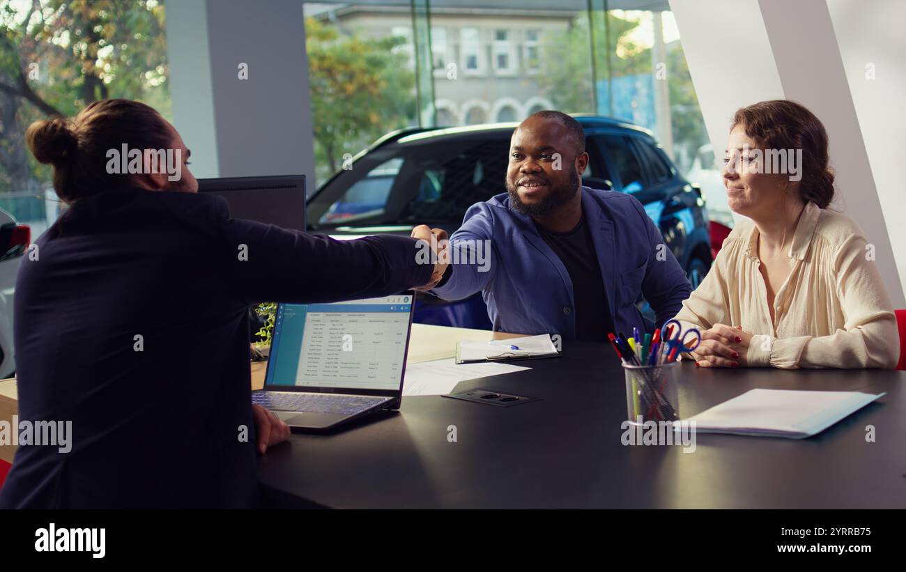 Verkäufer des Autohändlers schüttelt den zufriedenen Kunden die Hand ...