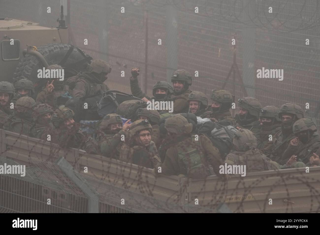 Israeli soldiers stand on an armoured vehicle before crossing the ...