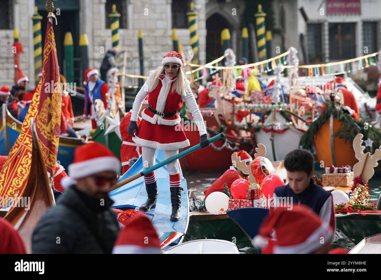 Menschen in Weihnachtsmannskostümen fahren Gondeln auf dem Canal Grande ...