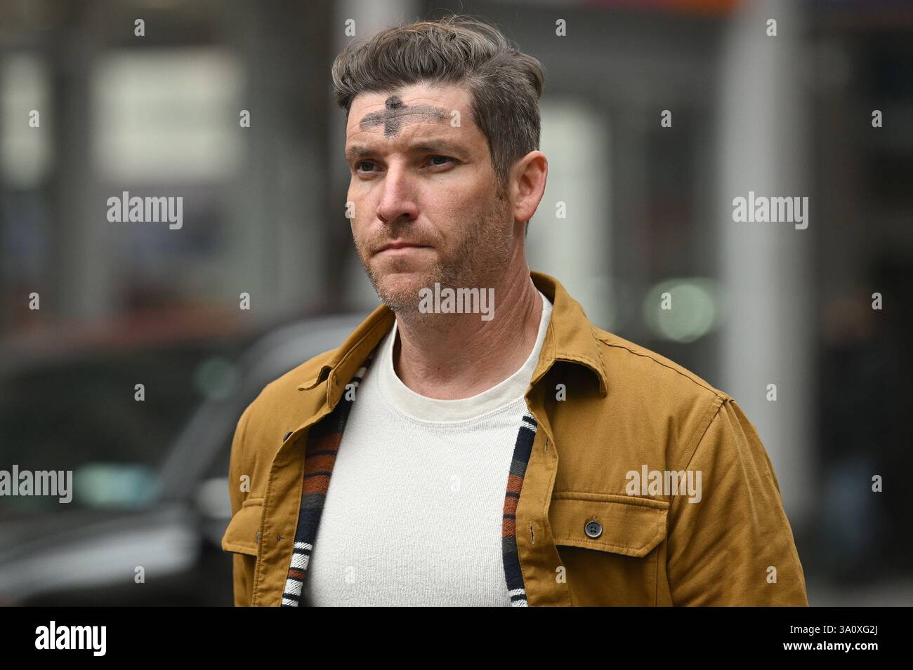 New York, USA. März 2025. Eine Fußgängerin ist mit einem Kreuz aus ...