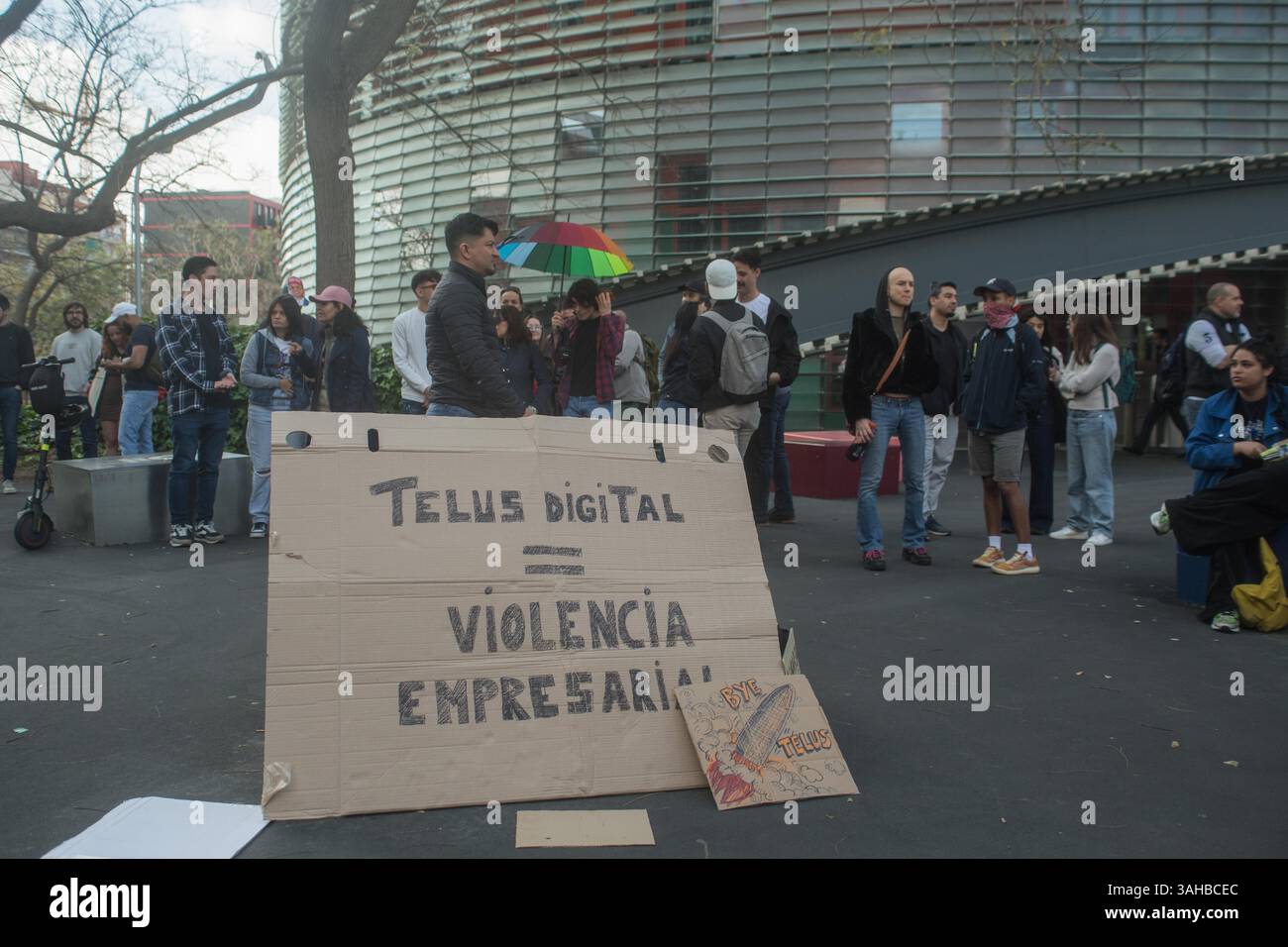 Es wird ein Plakat mit der Aufschrift „Telus digital = Corporate Violence“ und ein anderes mit ...