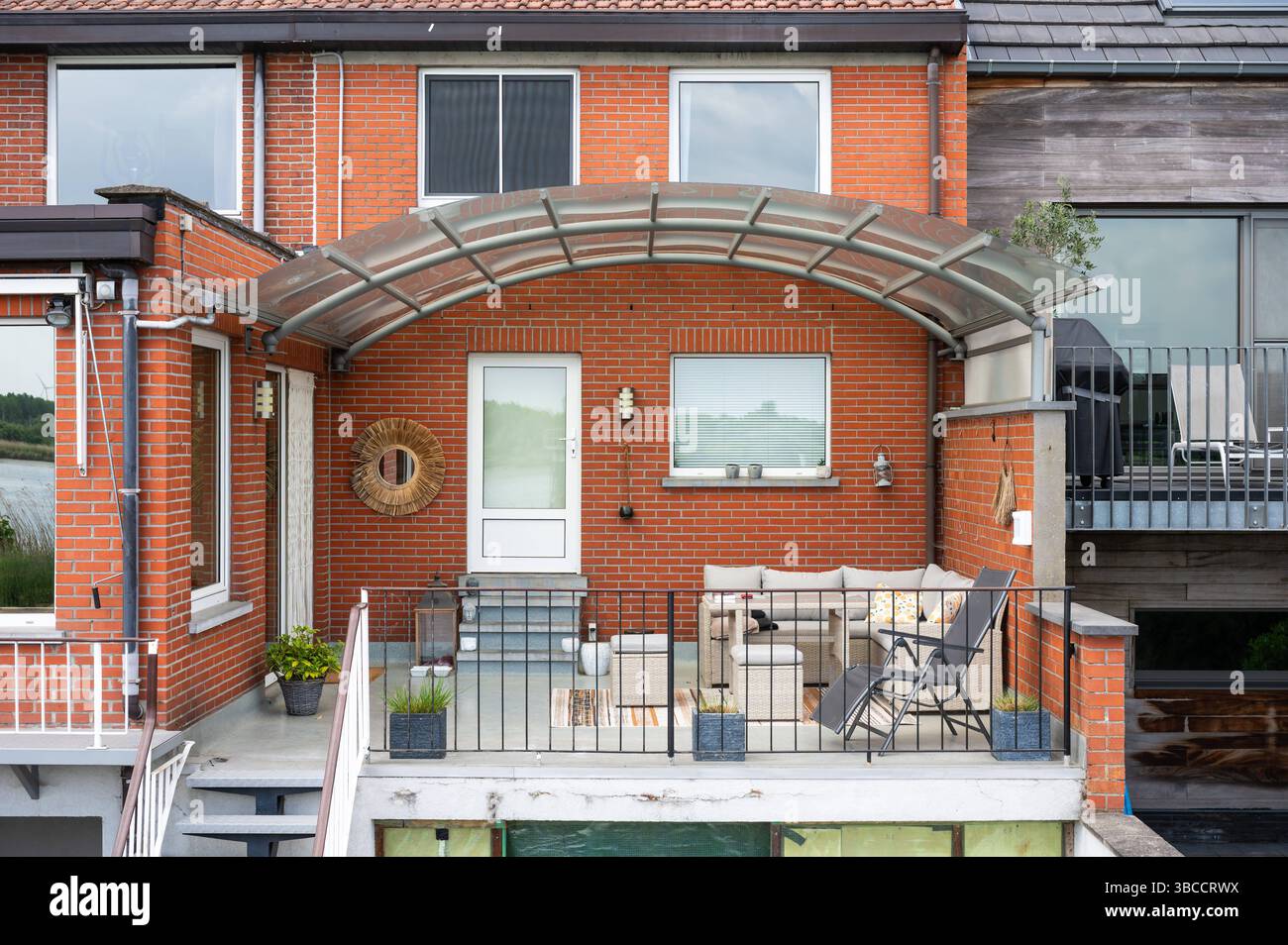 Ziegelsteinfassade mit Terrasse und Lounge-Sitzen am Ufer der Schelde ...