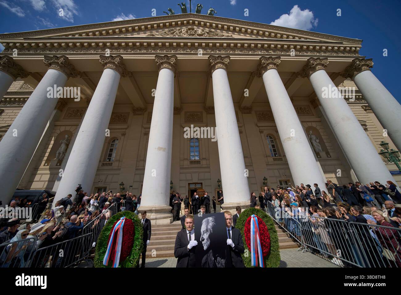 Funeral workers hold a portrait and a coffin with the body of famous ...