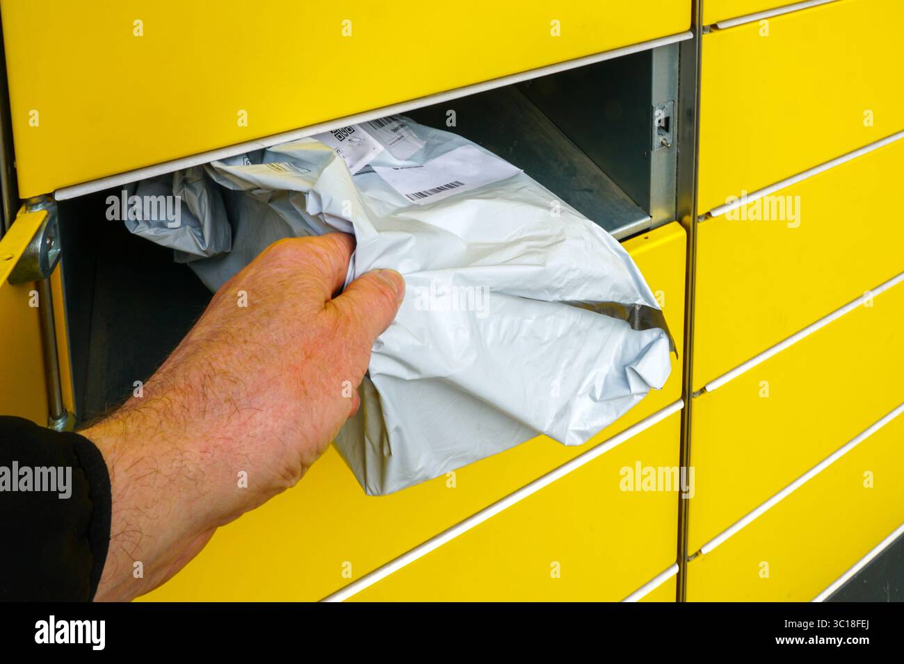 Eine Hand holt ein in Plastikverpackung verpacktes Paket aus einem ...