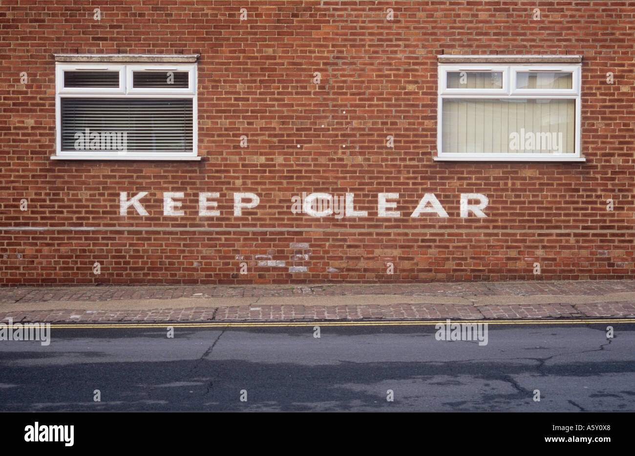 Ziegelmauer über verlassene Straße und mit zwei Fenstern mit ...