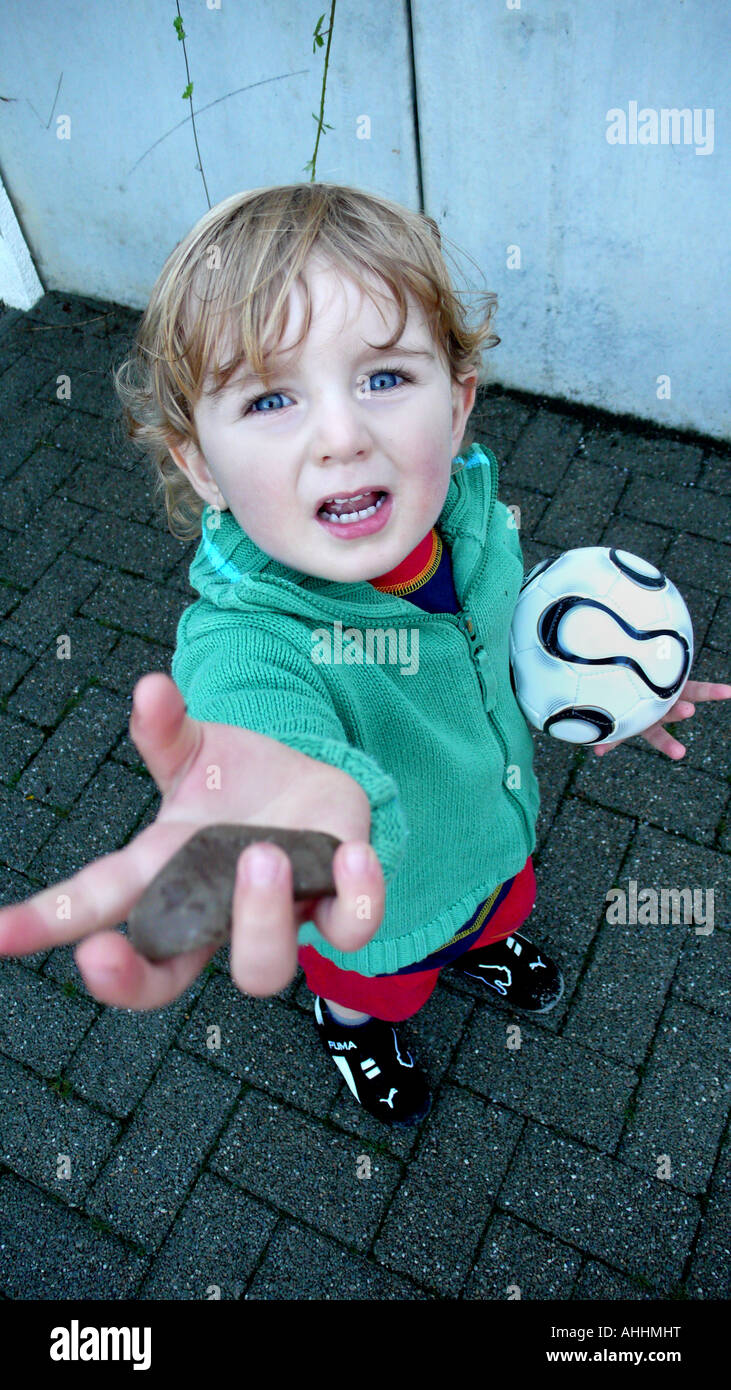 kleiner Junge mit Ball zeigt Stein Stockfotografie - Alamy