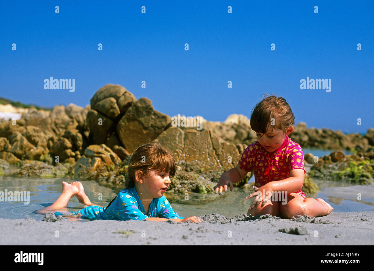 Zwei junge Mädchen (im Alter von 5 und 3) spielen im Sand am Strand ...
