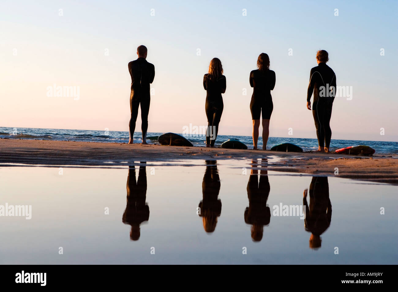 Vier Personen stehen am Strand mit Surfbrettern Stockfotografie - Alamy