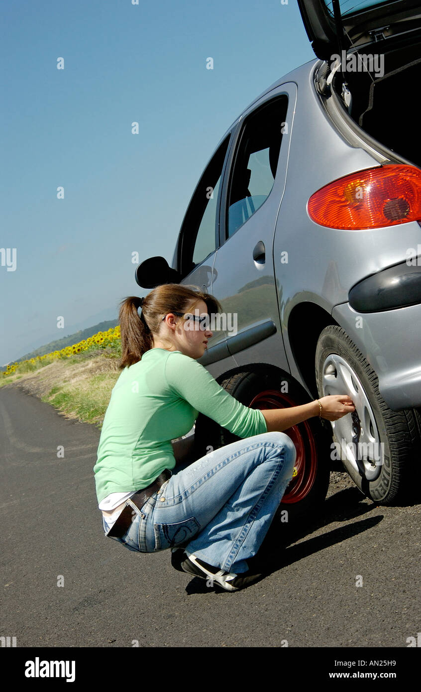 Frau der Radwechsel / Reifen für einen Ersatz Reifen auf ihrem Auto ...