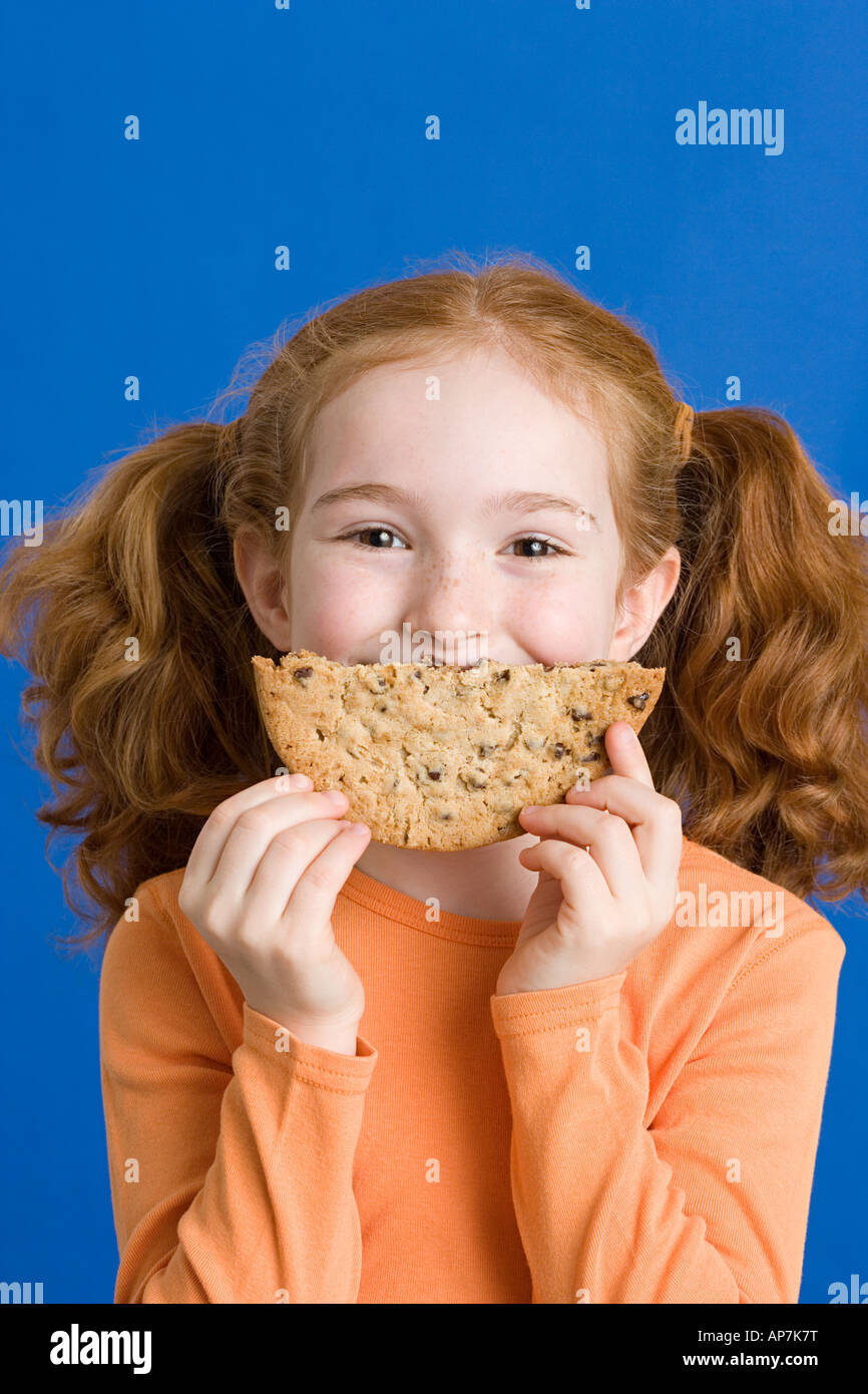 Mädchen, die einen Cookie über den Mund halten Stockfotografie - Alamy