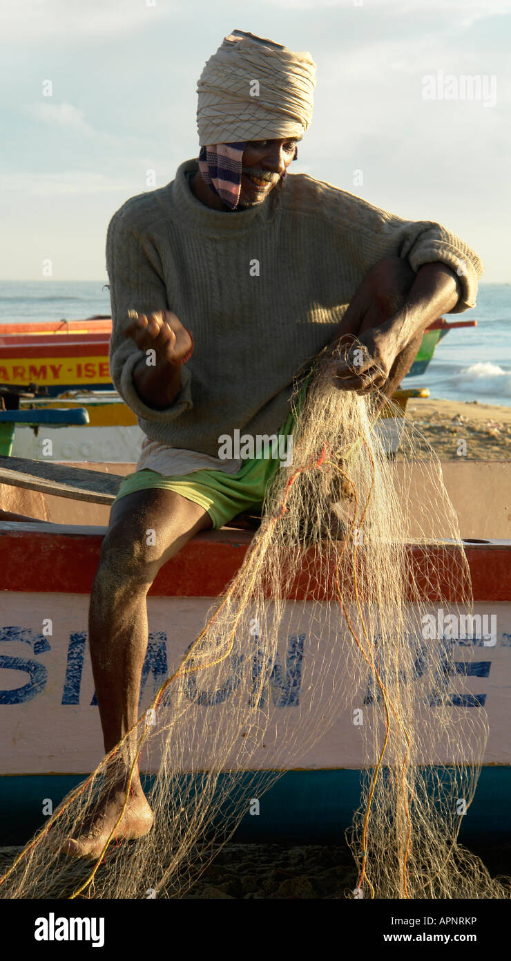 indische Fischer seine Fischernetze am Strand von Chennai ausbessern ...