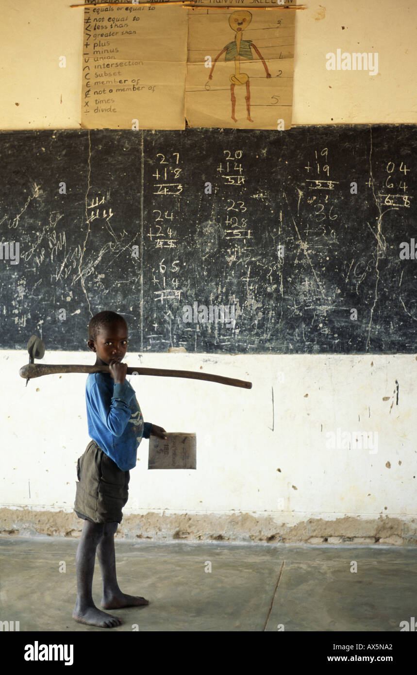 Mbati, Sambia. Junge mit Hand Pflug über die Schulter hält ein Buch im ...