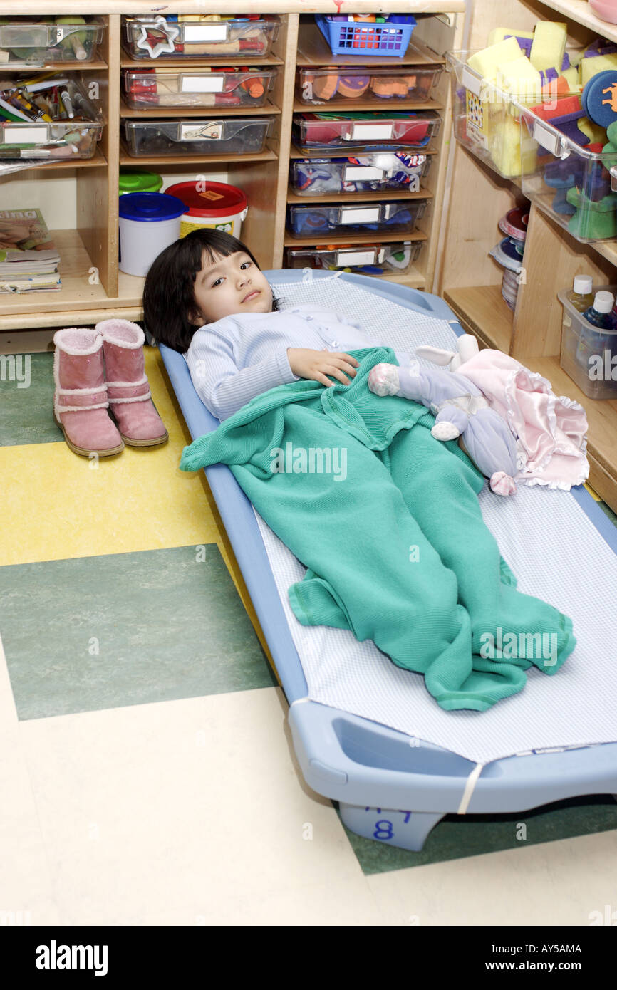 4 Jahre alte Kindergarten Mädchen liegend auf einem Feldbett während ...