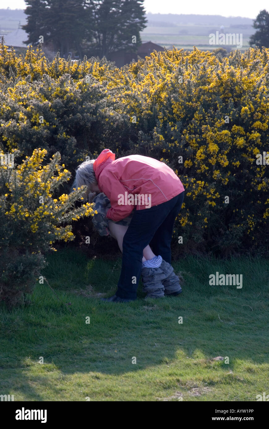 Mutter Helping Young Boy haben Pipi, wenn kurze, auf einem Spaziergang ...