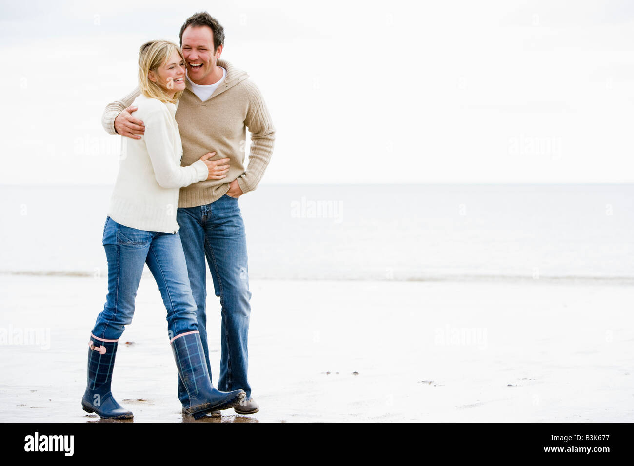 Paare, die am Strand Arm in Arm zu Lächeln Stockfotografie - Alamy