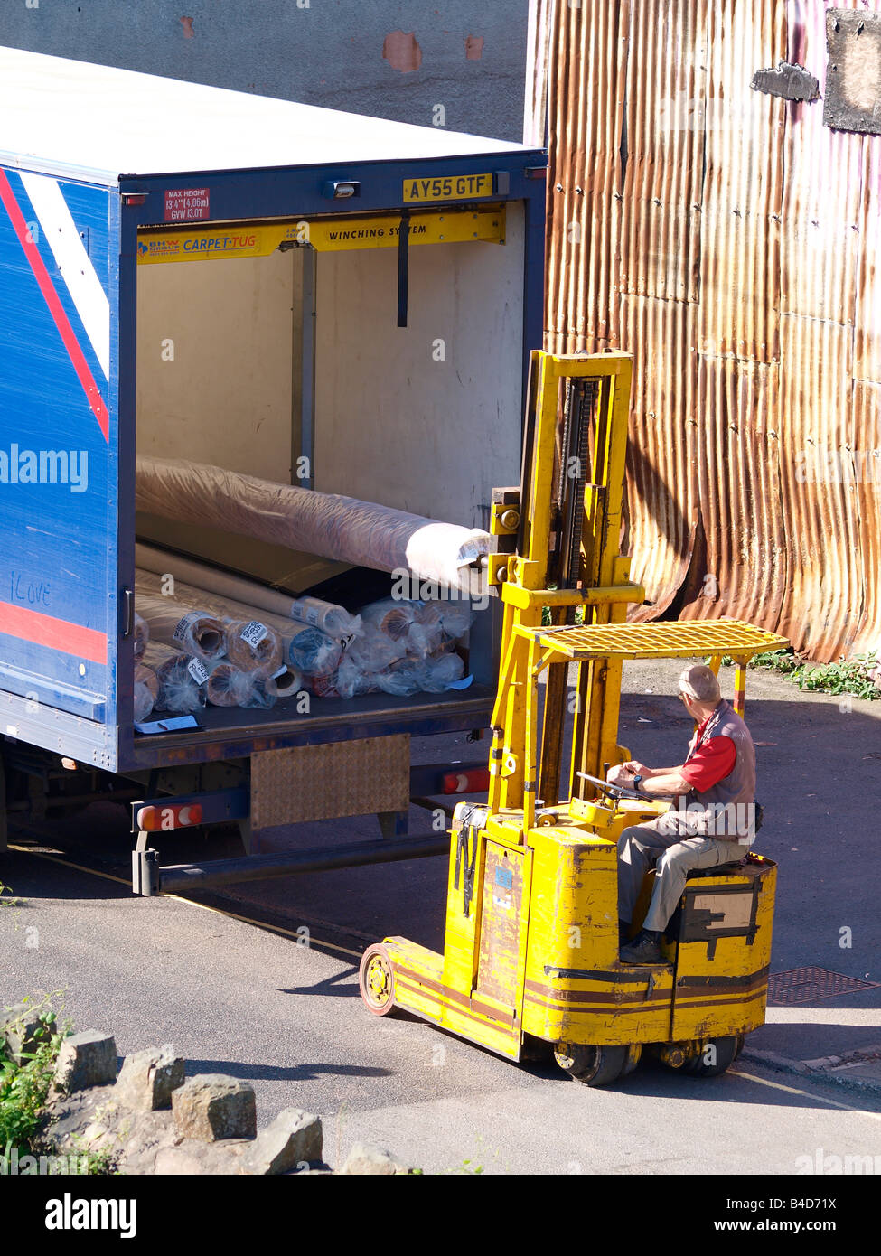Arbeiter einen Gabelstapler entladen Teppiche aus einem LKW in Betrieb ...