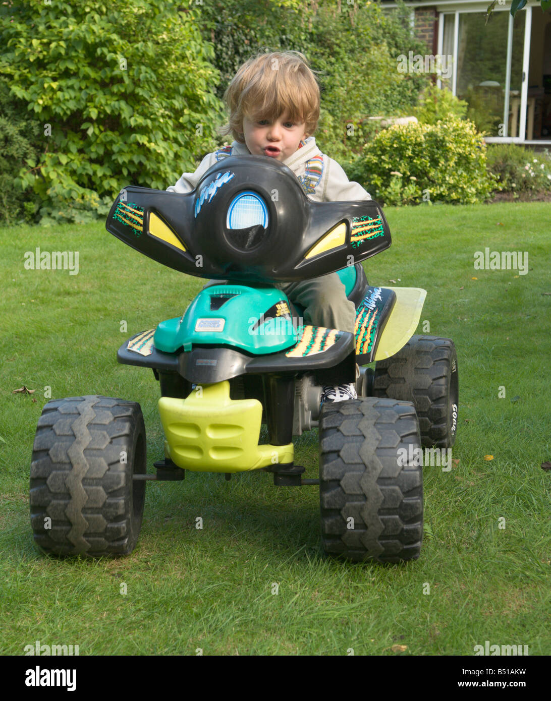 Junge Kind auf das Kind das Quad fahren der Maschine im Garten UK ...