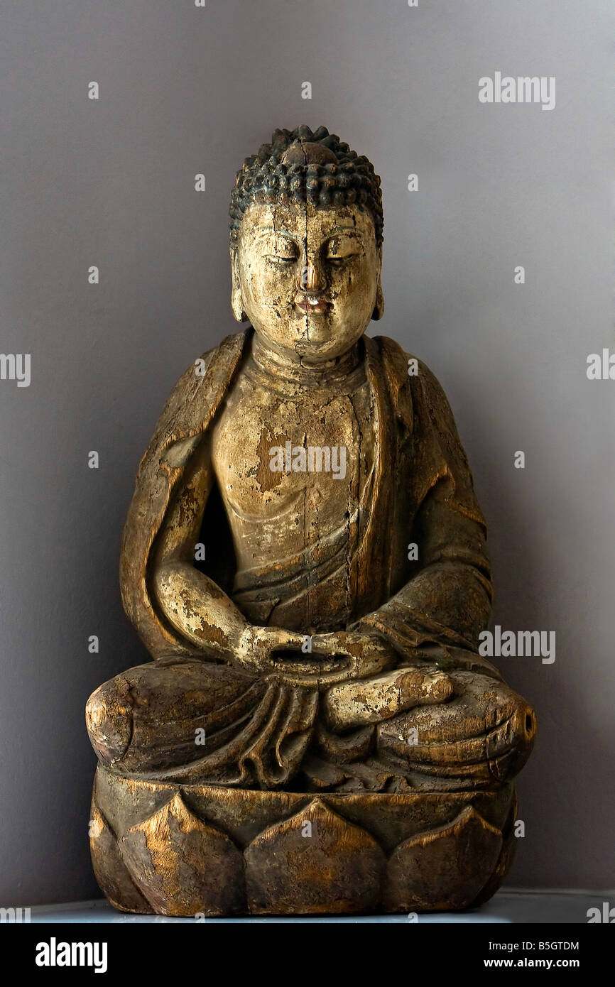 Eine hölzerne Statue des Buddha sitzt im Lotussitz auf grau isoliert ...