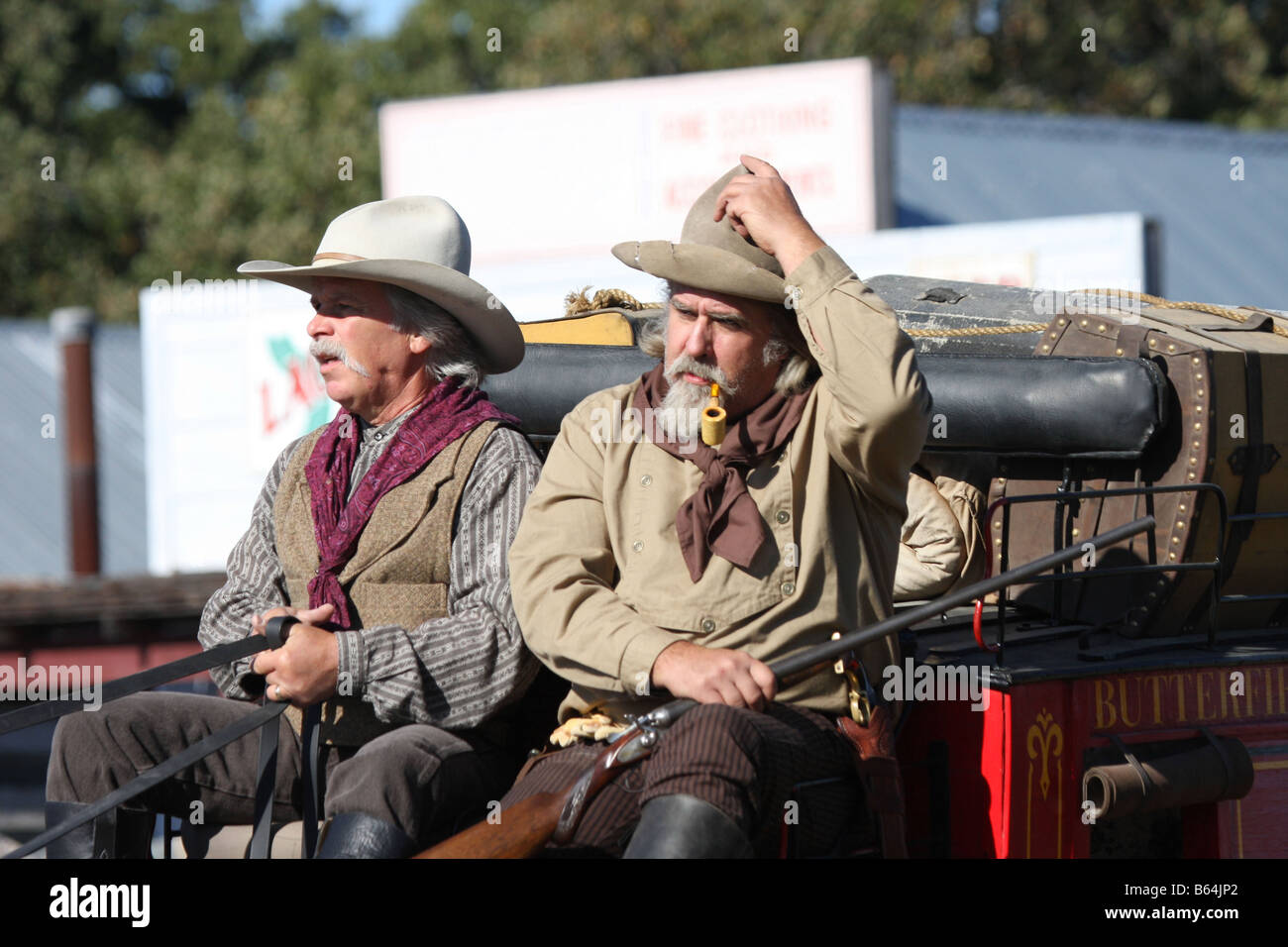 Zwei Cowboys der Postkutsche durch eine alte Westernstadt fahren ...