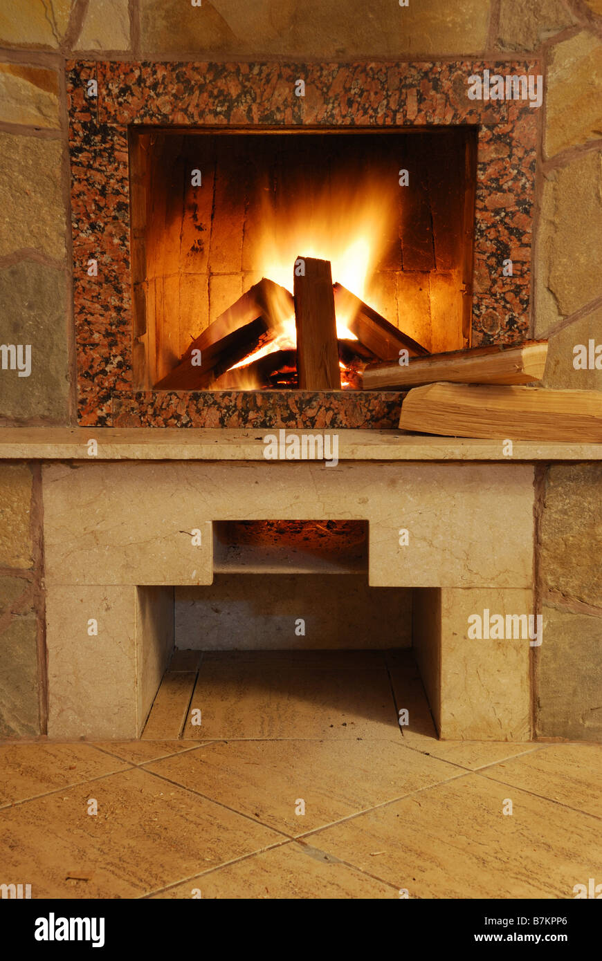 Kamin Flaring Feuer in einem Kamin, der Reveted wilde Stein und Marmor ...