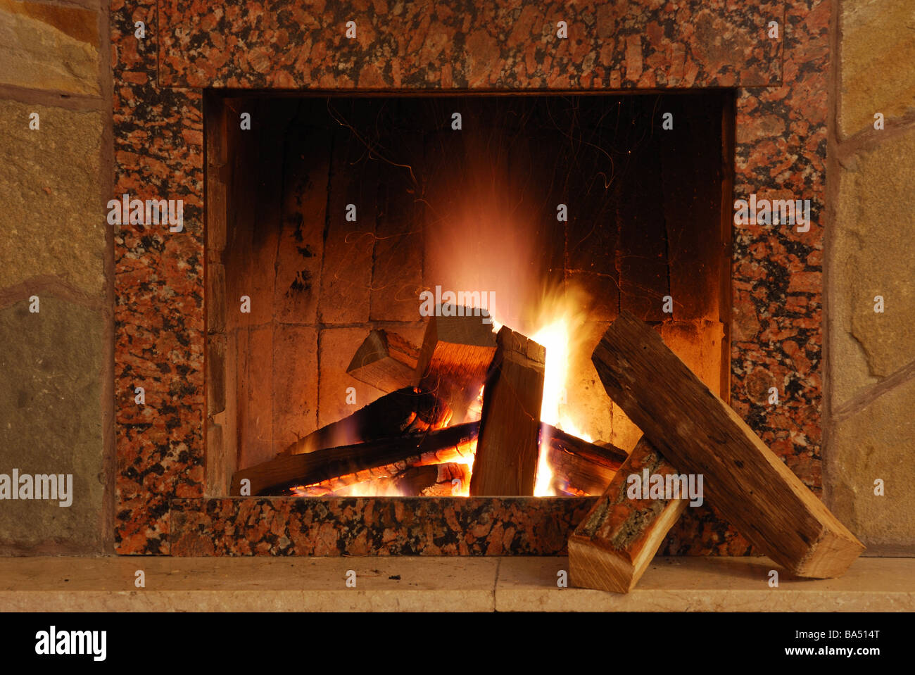 Kamin Flaring Feuer in einem Kamin, der Reveted wilde Stein und Marmor ...