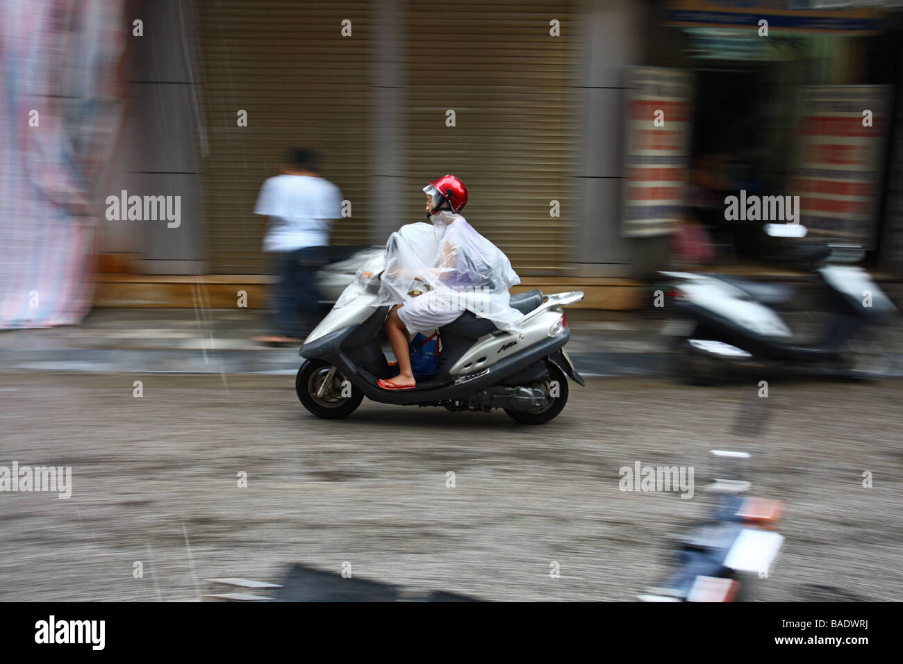 Schwenken. Straßenszene. Frau mit ihrem Motorroller, Motorrad unter dem ...