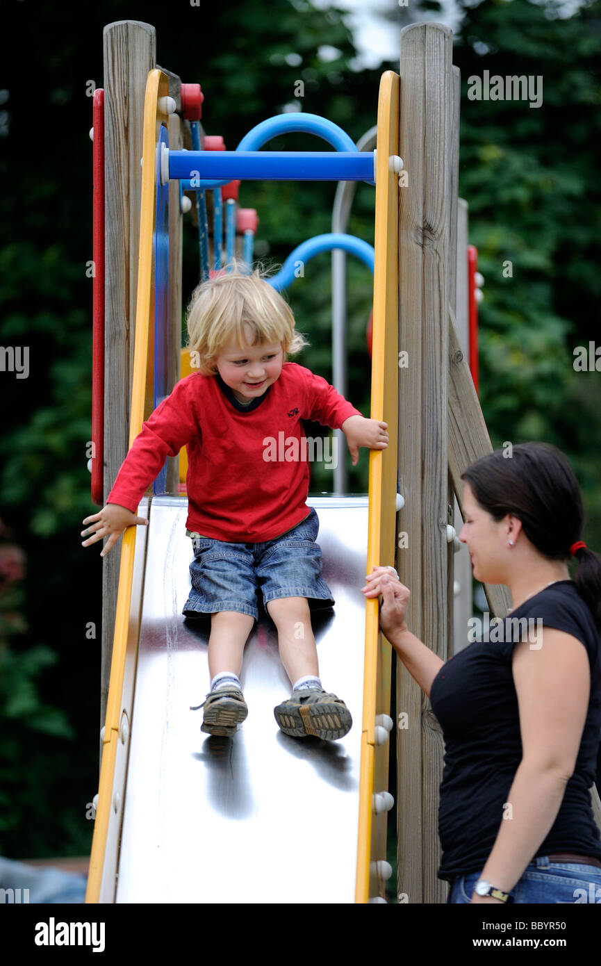 Blonde junge Kind rutscht die Rutsche auf dem Spielplatz ...