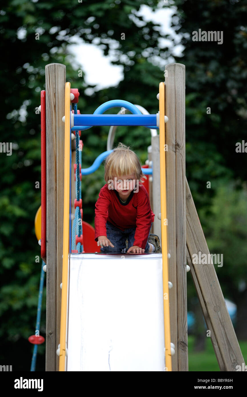 Blonde junge Kind rutscht die Rutsche auf dem Spielplatz ...