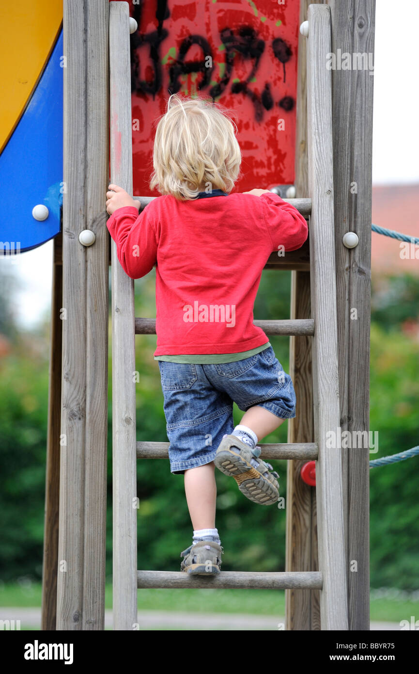 Blonde junge Kind rutscht die Rutsche auf dem Spielplatz ...