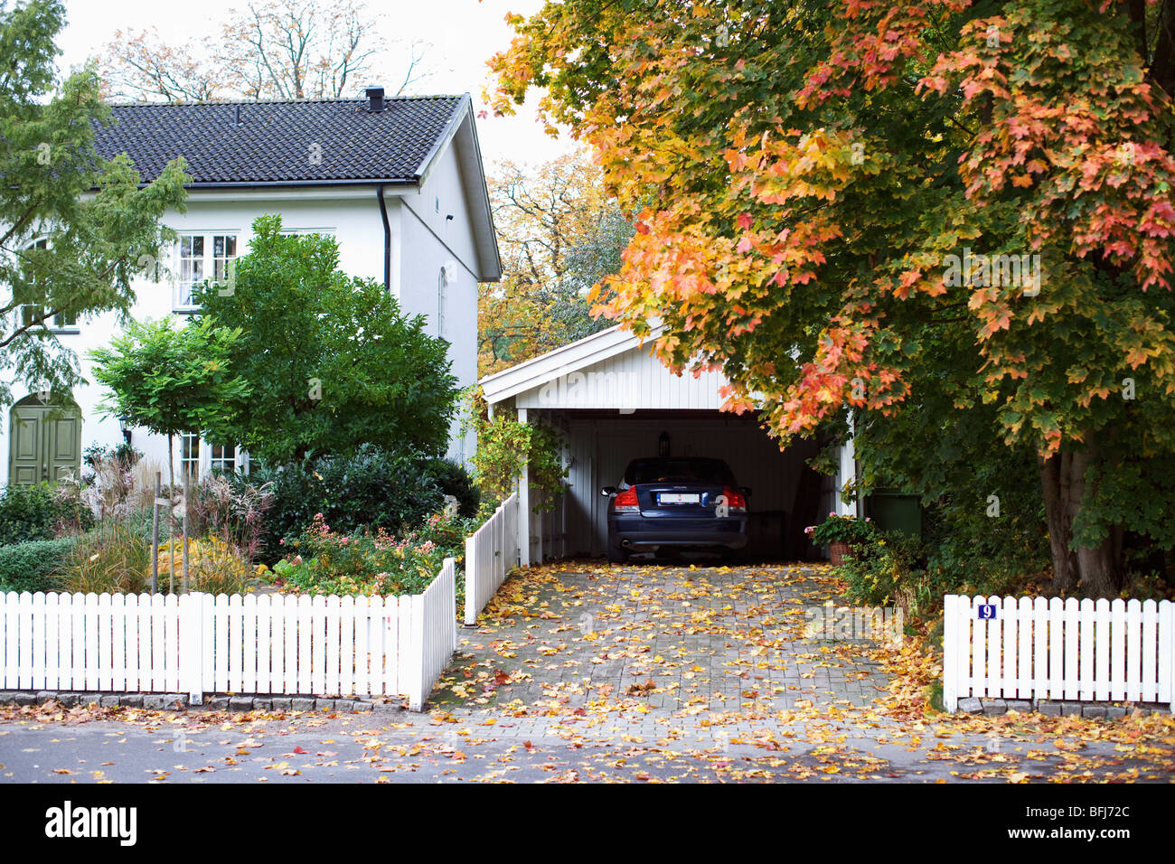 Eine Garage mit einem geparkten Auto durch ein weißes Haus, Schweden ...