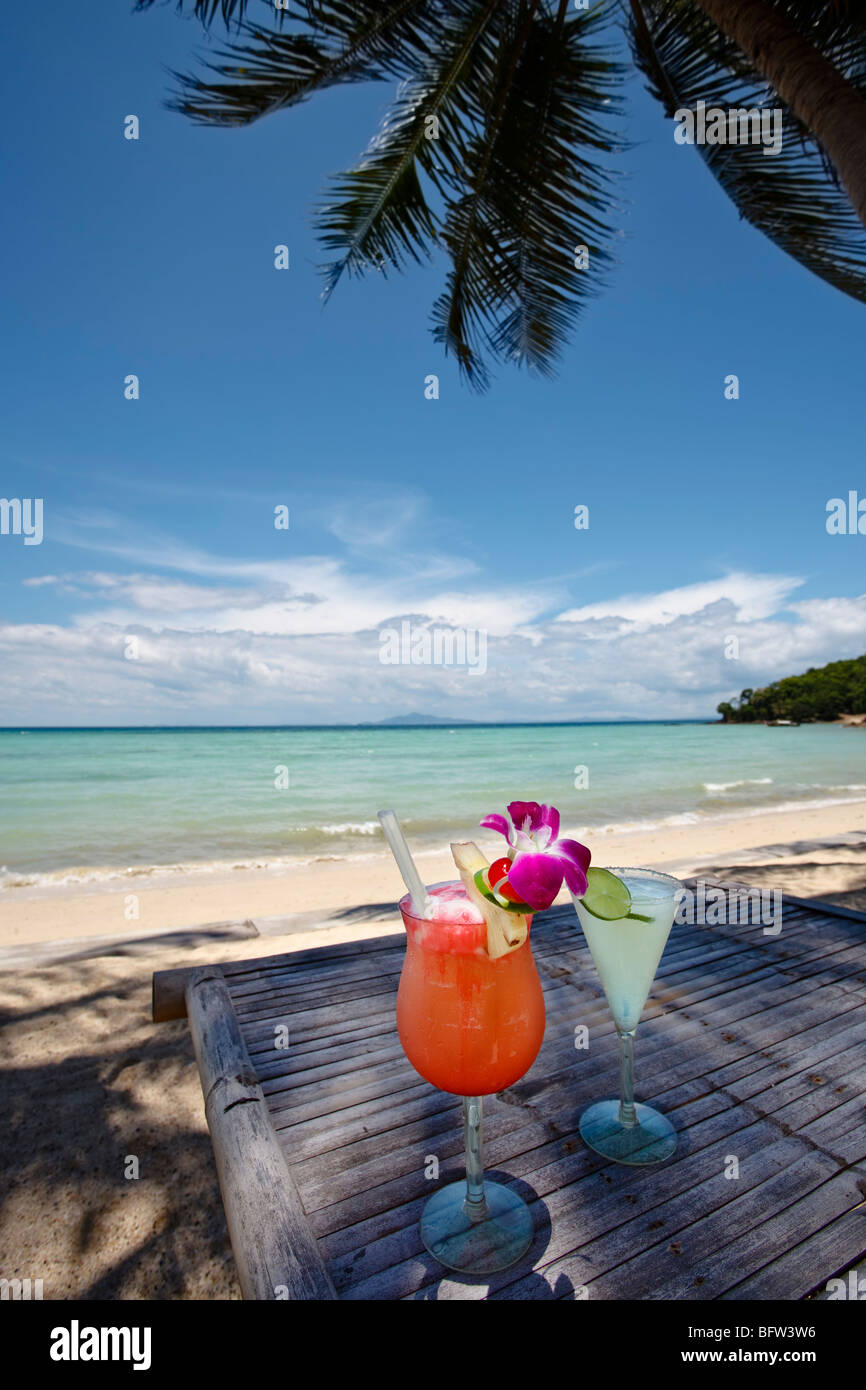 Paar Cocktails unter Palmen mit einem schönen Strand im Hintergrund ...