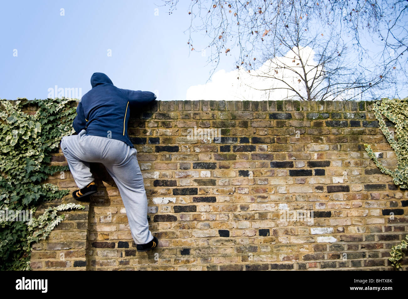 Ein junger Mann über eine Mauer klettern Stockfotografie - Alamy