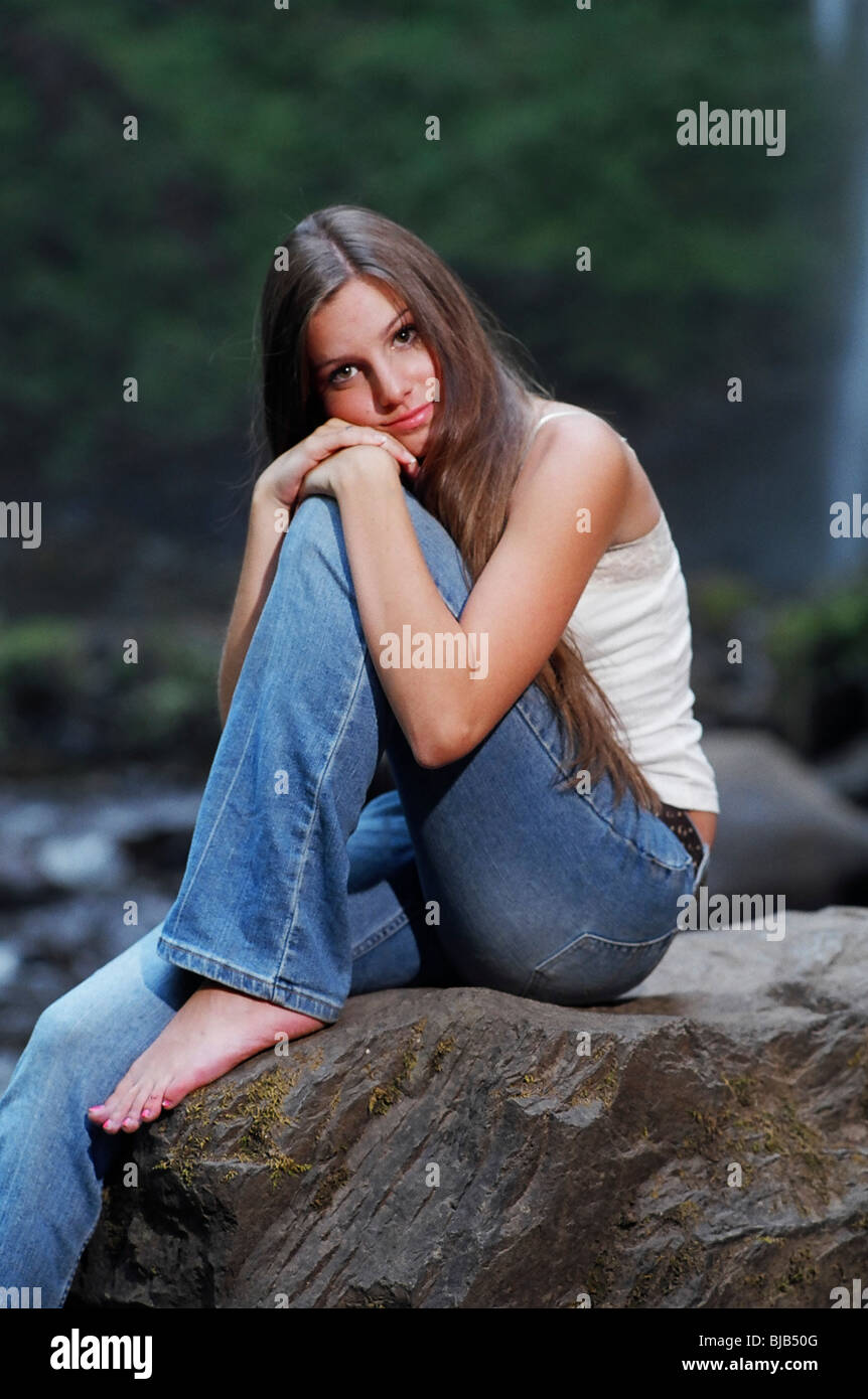 barfuß Teenager-Mädchen auf einem Felsen sitzend und Blick auf den ...