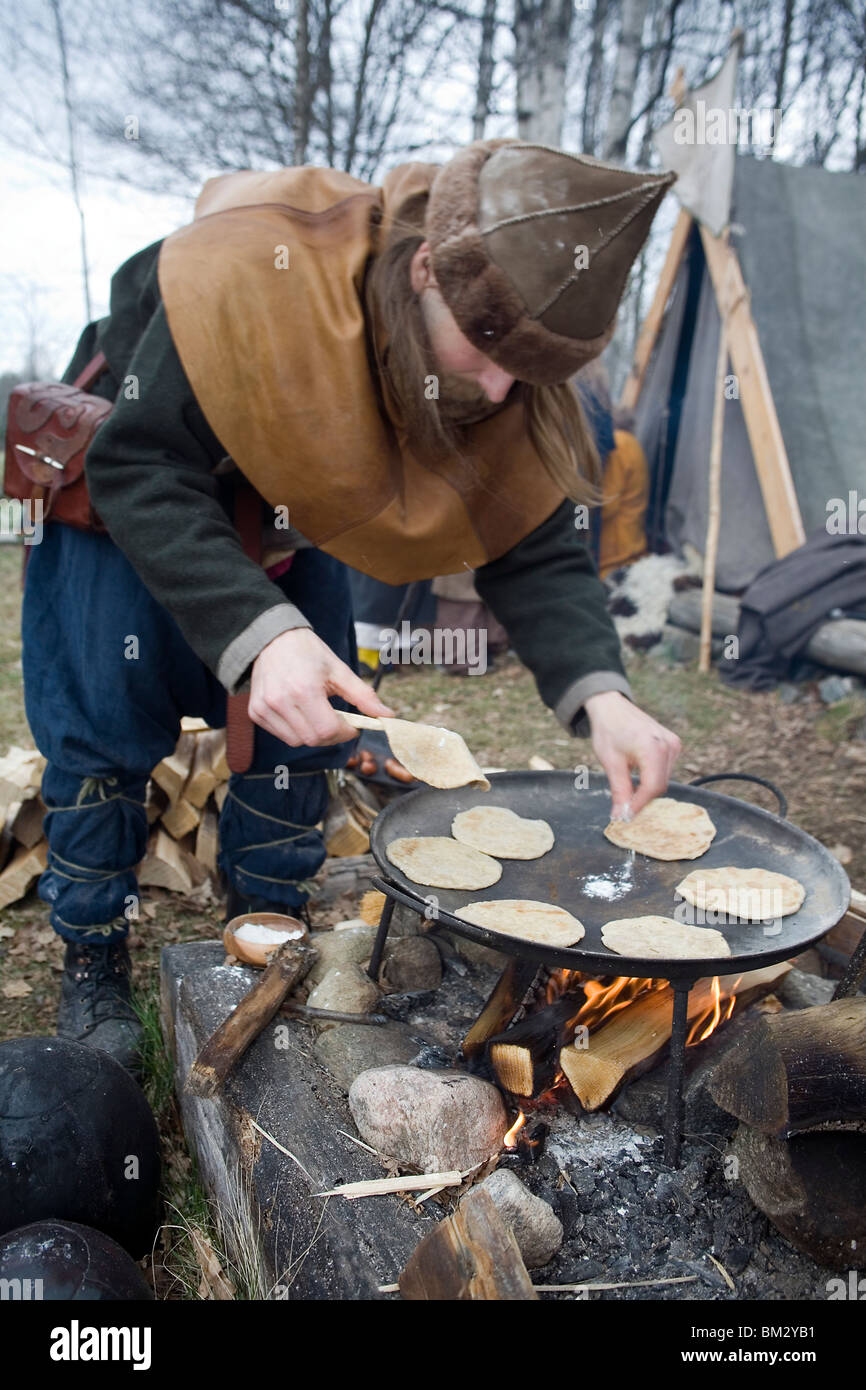 Wikinger Reenactment. Mann in Viking Roben backt Fladenbrot am offenen ...