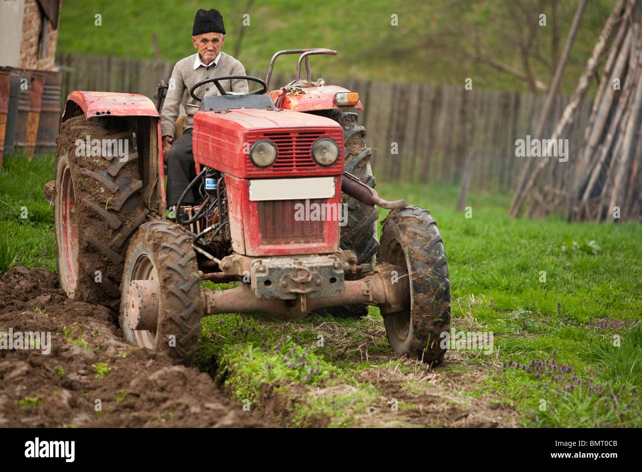 Senior Bauer mit einem alten Traktor, sein Land zu pflügen ...