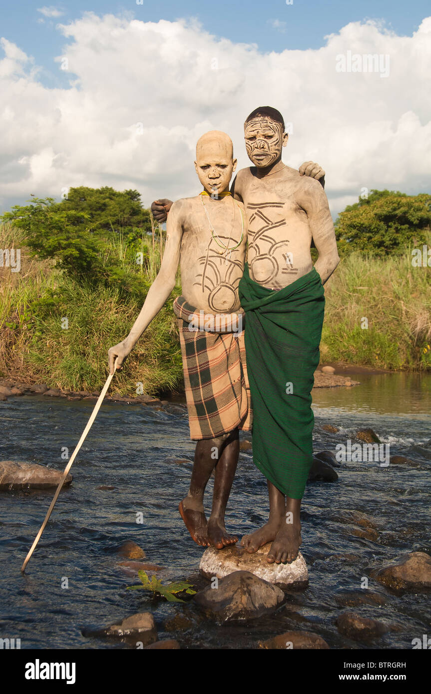 Surma Mann und Knabe mit Körper-Bilder stehen in den Fluss Kibish, Omo ...