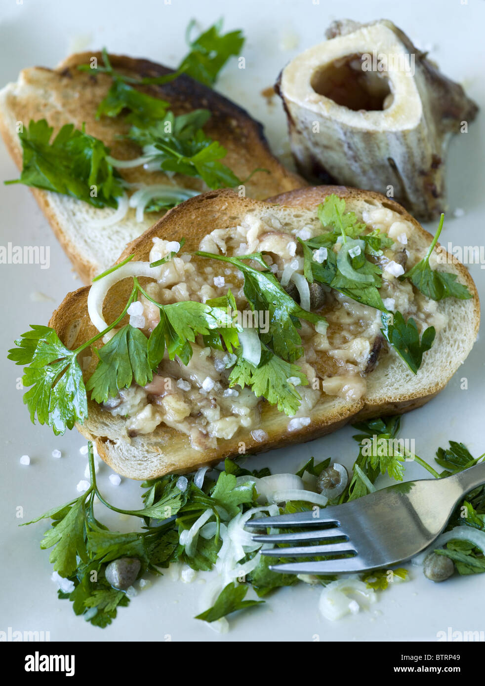 Gebratenes Knochenmark serviert mit Toast und Petersilie und Zwiebeln ...