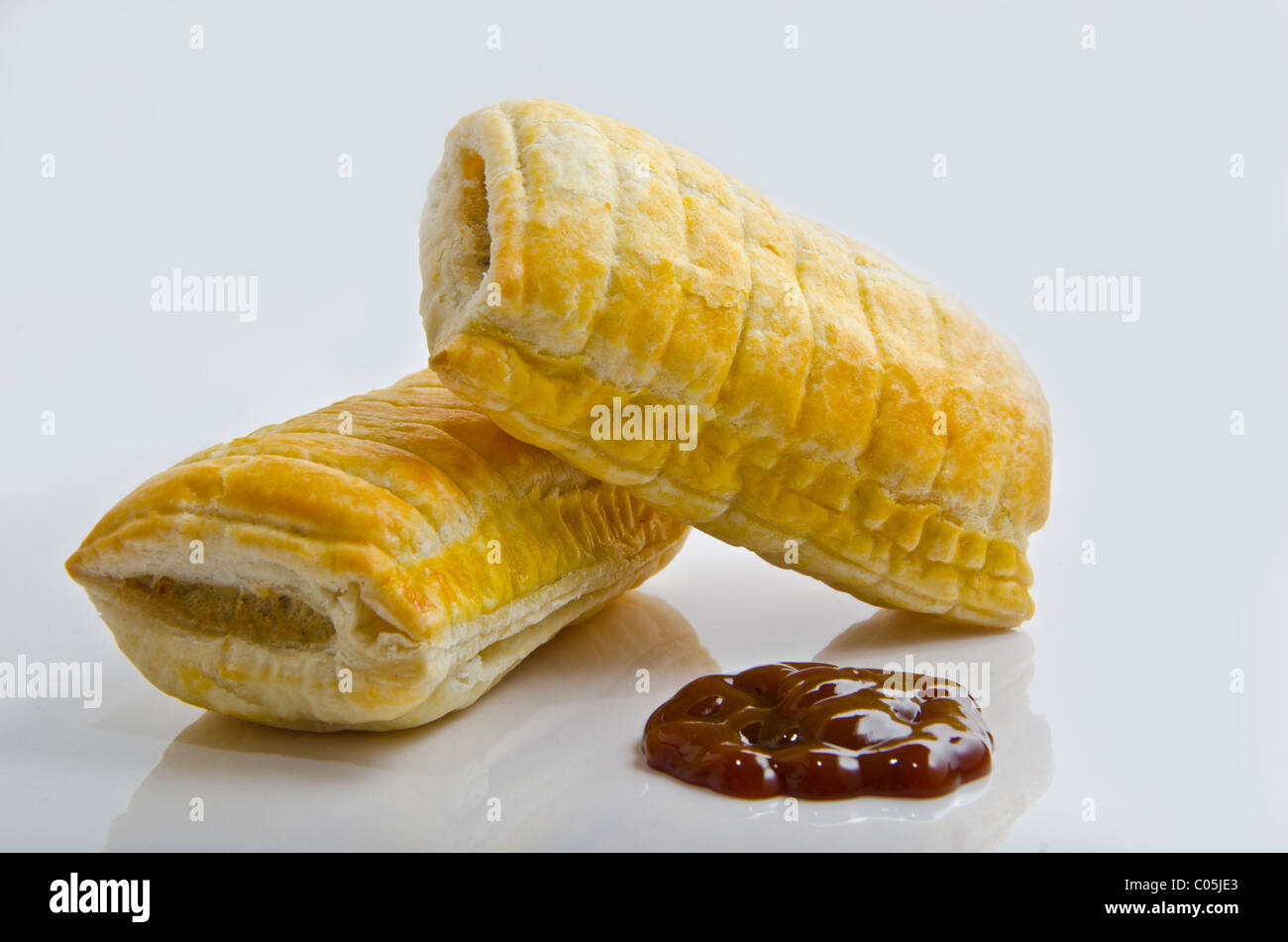 Zwei Wurstbrötchen auf weißem Hintergrund mit brauner Soße ...