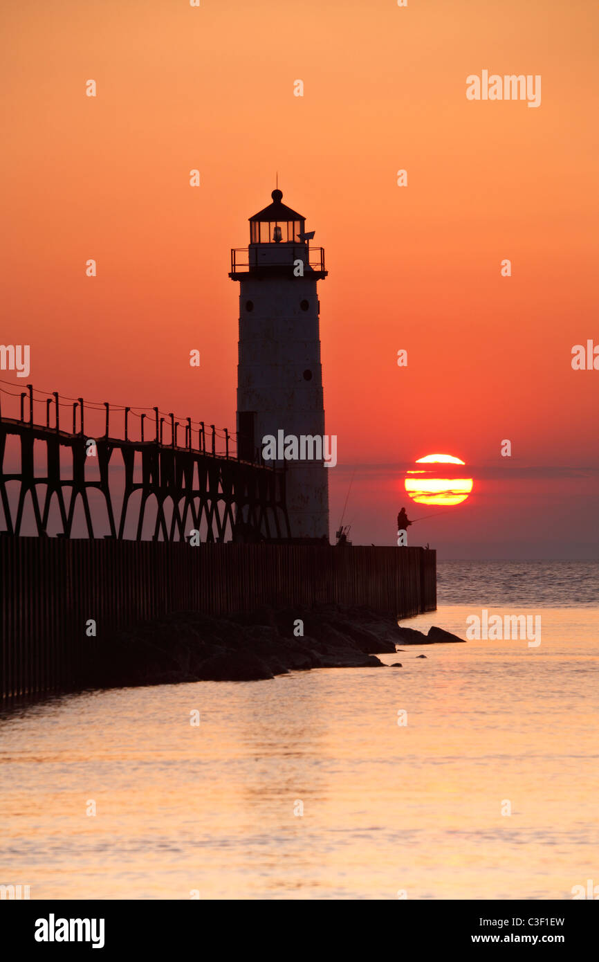 Ein einsamer Fischer ist am Fuße des Leuchtturms an einem Sommerabend ...