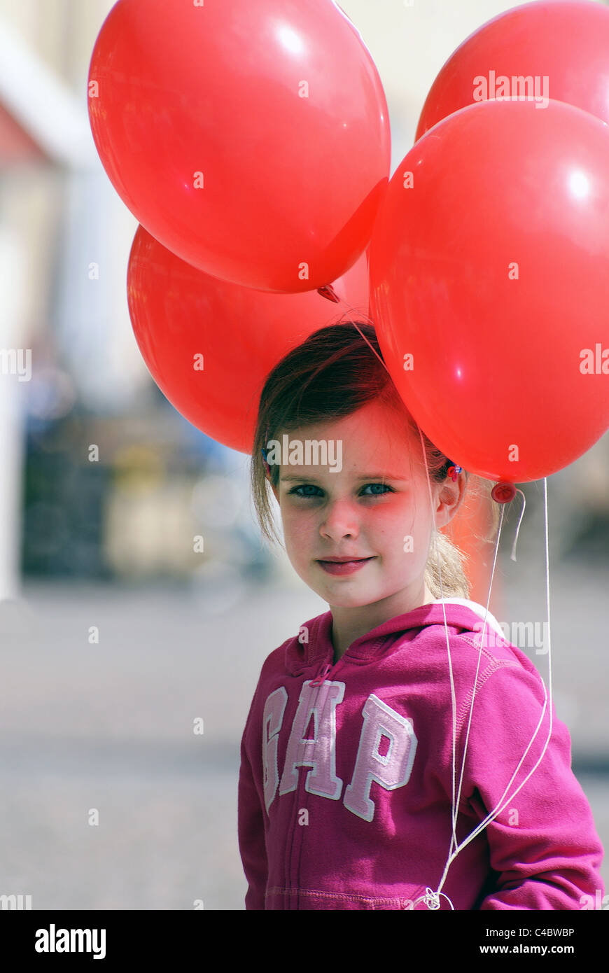 Lächelnde Mädchen in lila mit vier roten Luftballons Stockfotografie ...