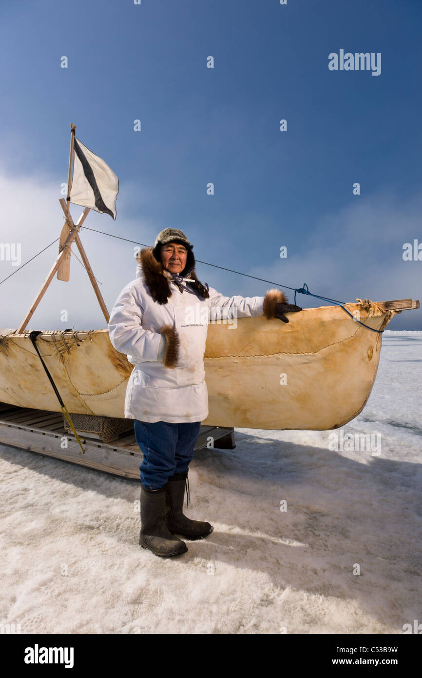Männliche Inupiaq Eskimo Jäger steht neben einem Umiaq mit ...