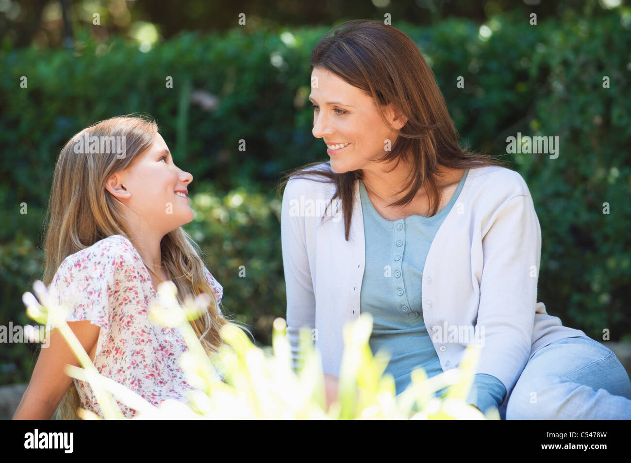 Niedliche kleine Mädchen und ihre Mutter zusammen im Garten zu sitzen Stockfotografie - Alamy