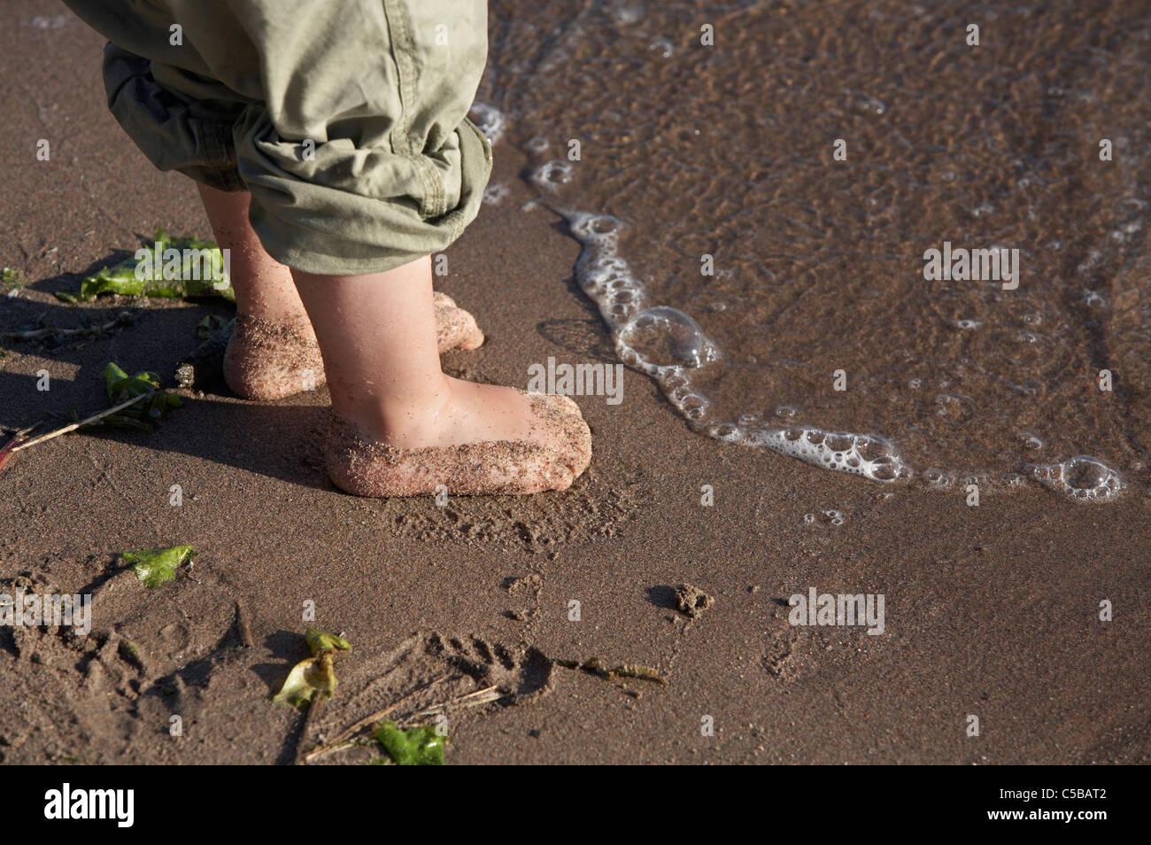 Geringen Teil ein Kind barfuß am Wasserrand am Strand stehen ...